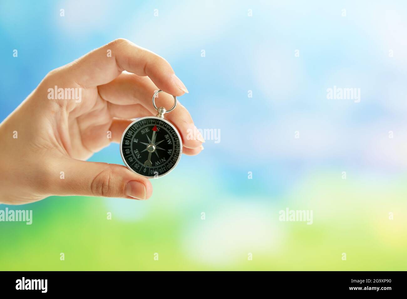 Female hand with compass on bright blurred background Stock Photo - Alamy