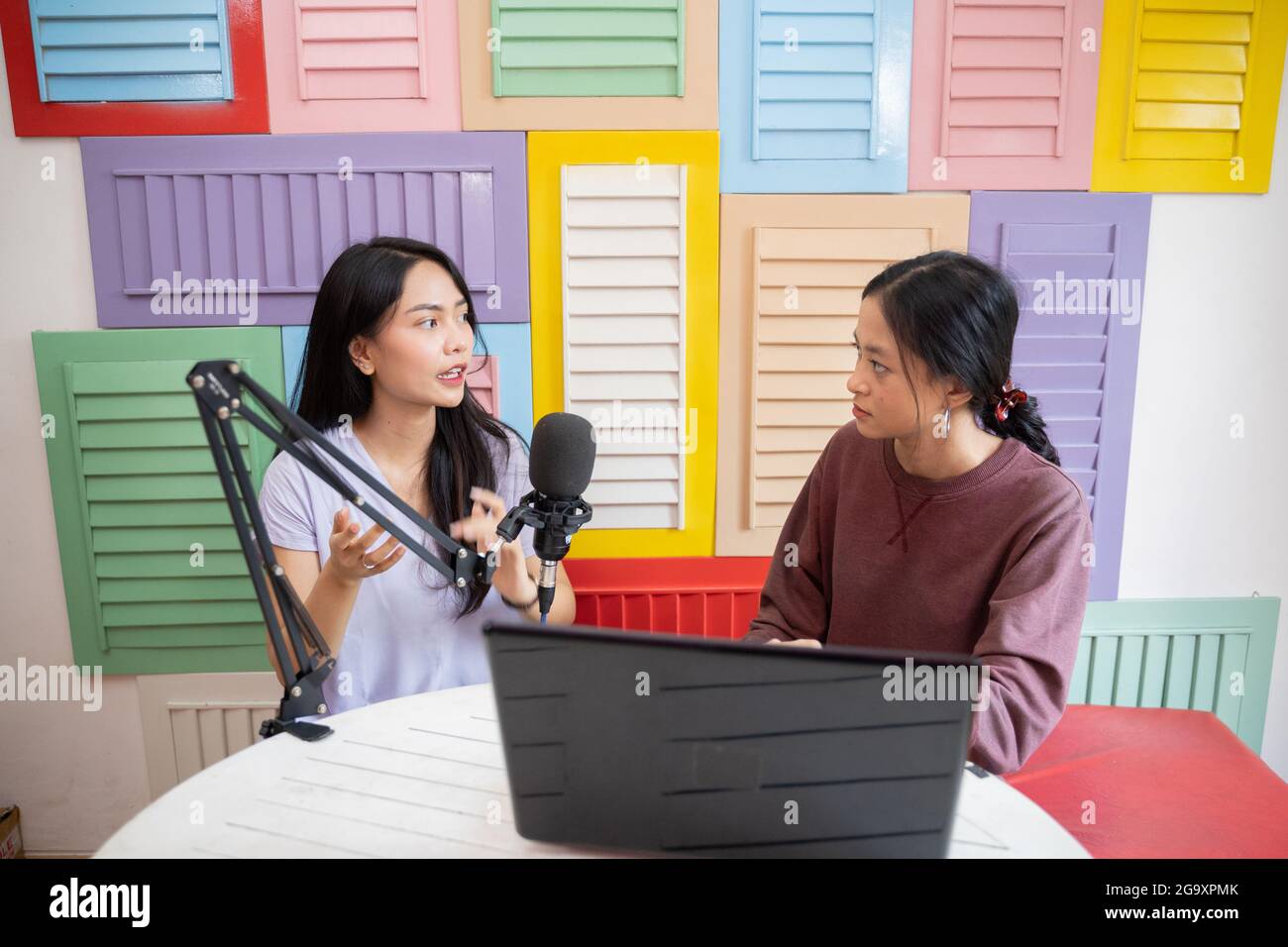 two women talking seriously and using microphones while recording ...