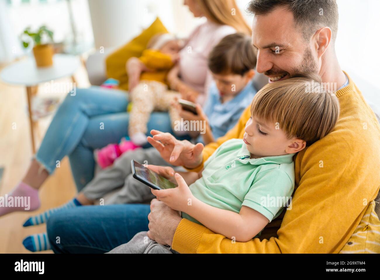 Happy father with children playing video game on smart phone at home ...