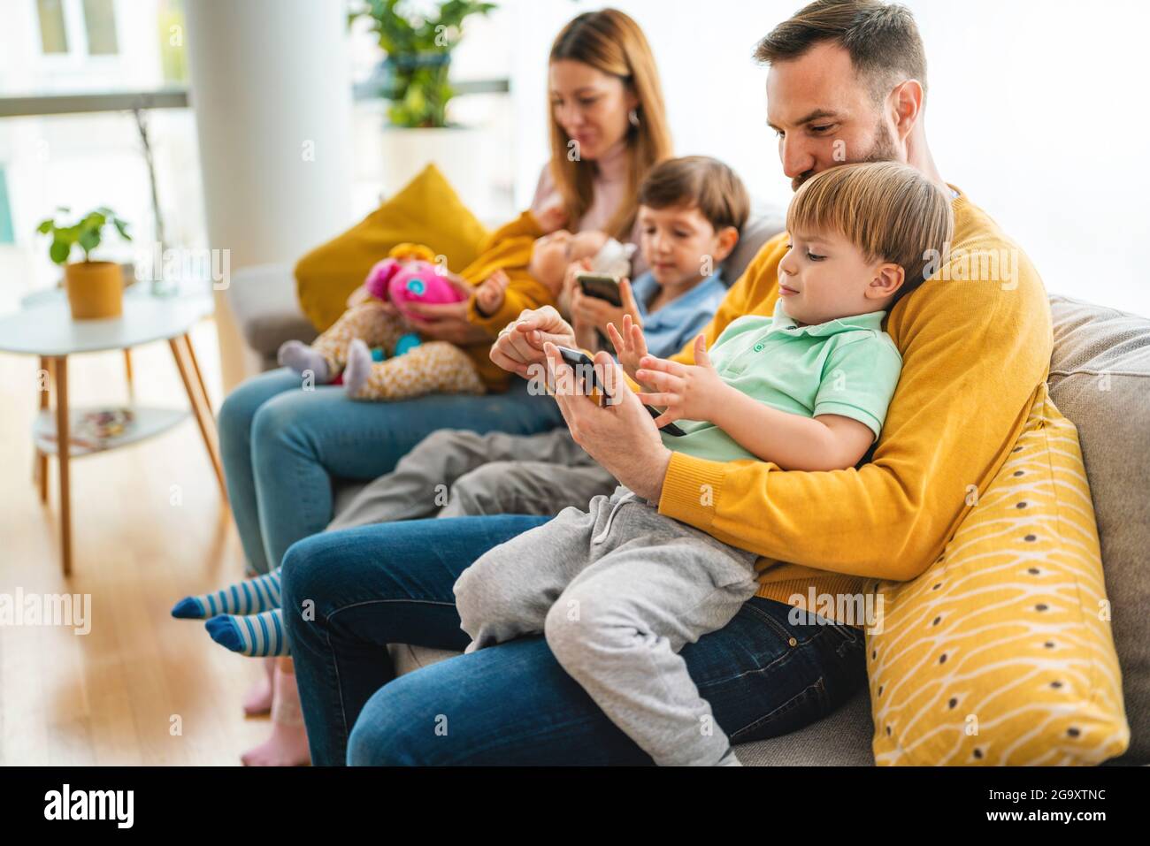 Parents with children playing games, using mobile apps on phone at home ...