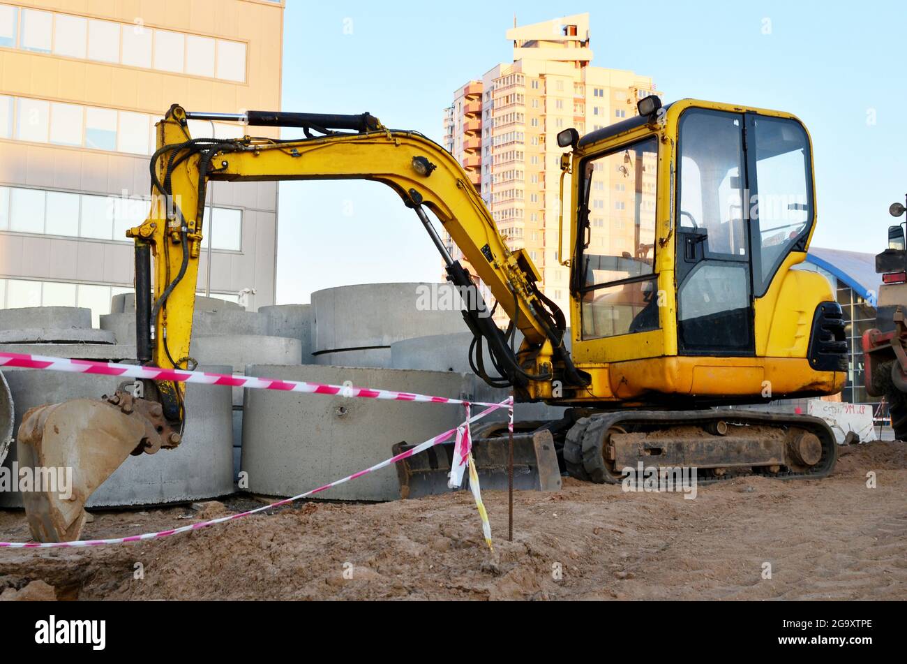 Mini excavator during laying external sewer pipes at construction site ...