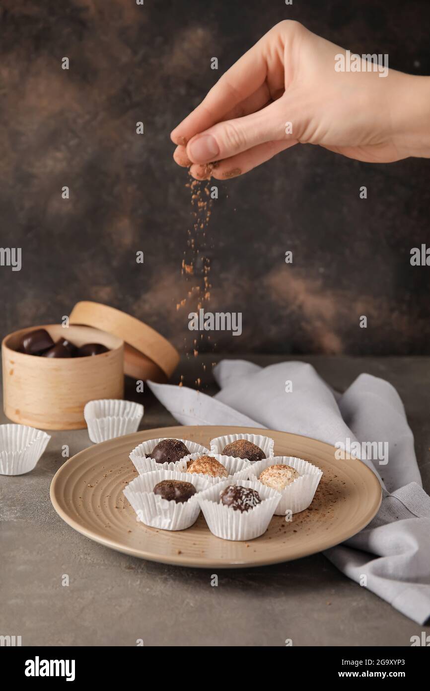 Female hand sprinkling cacao powder onto sweet chocolate candies on ...