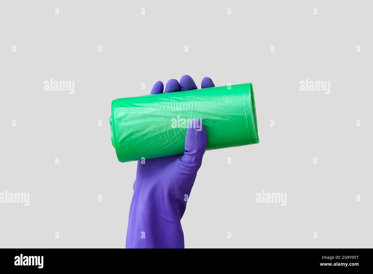 Hand in rubber glove with roll of garbage bag on light background Stock ...