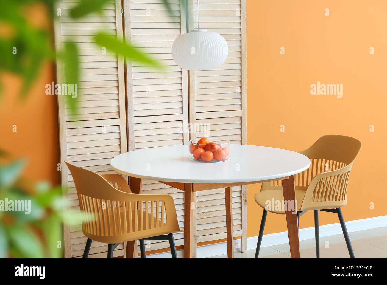 Dining table and folding screen near color wall Stock Photo - Alamy
