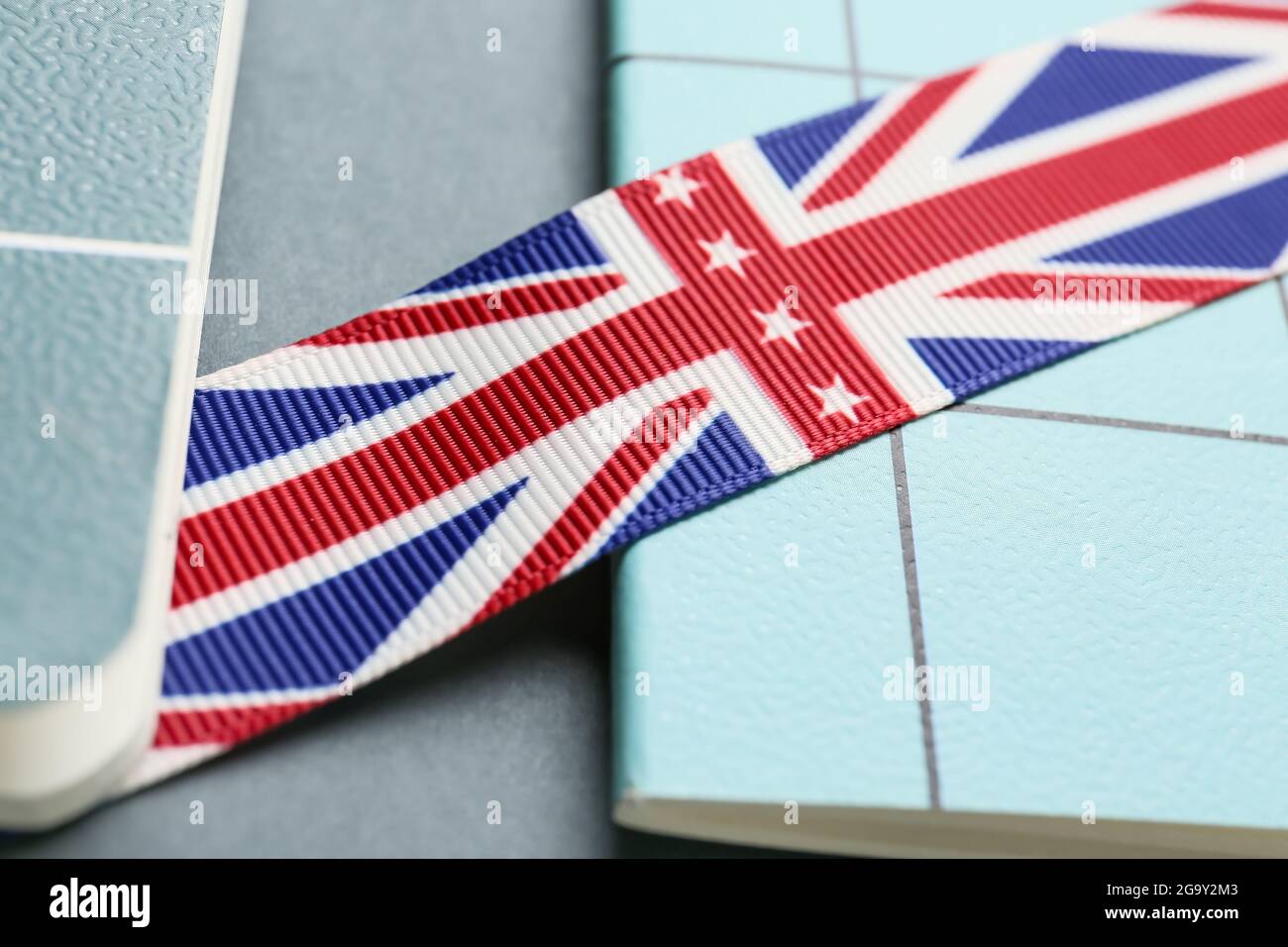 Notebooks and ribbon in colors of UK flag on grey background, closeup ...