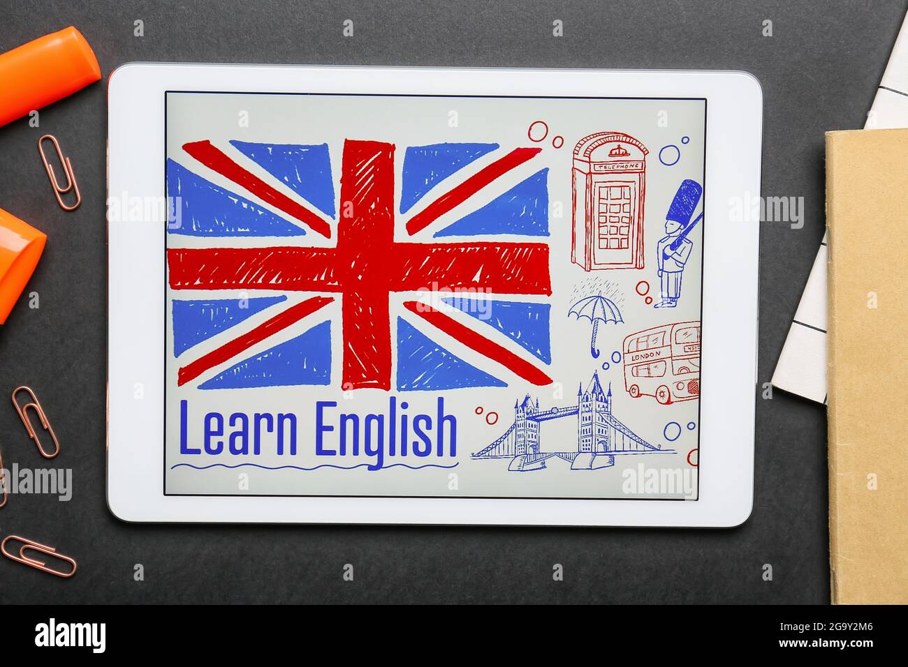 Tablet computer and stationery on dark background. Concept of learning ...