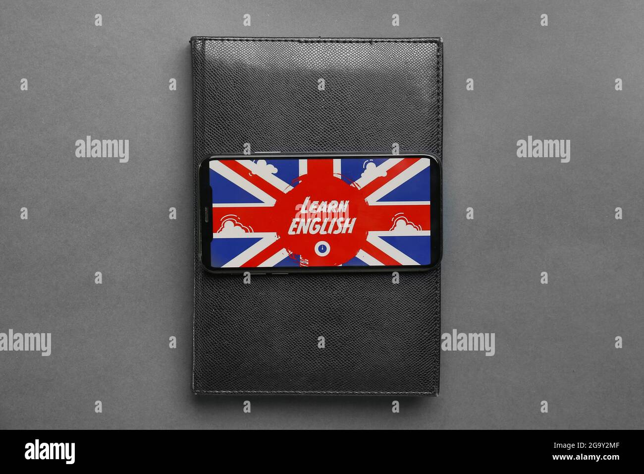 Notebook and phone with UK flag on screen against grey background ...