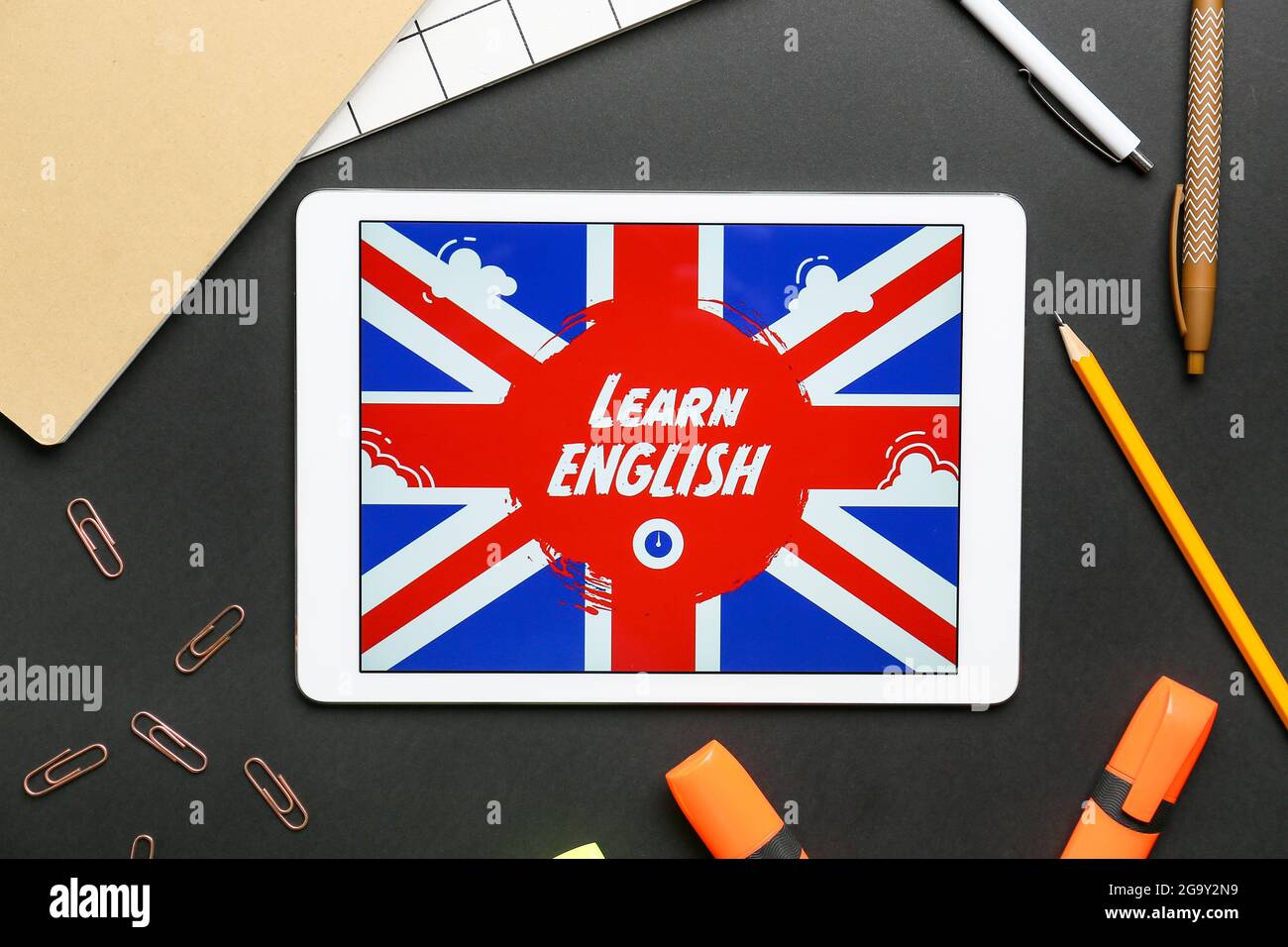 Tablet computer and stationery on dark background. Concept of learning ...