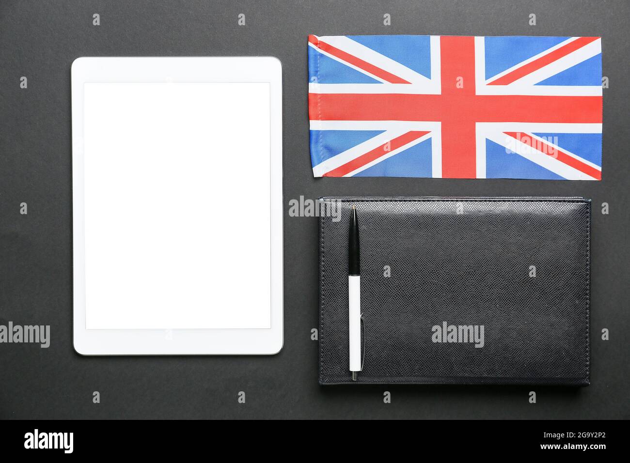Tablet computer, notebook and UK flag on dark background. Concept of ...