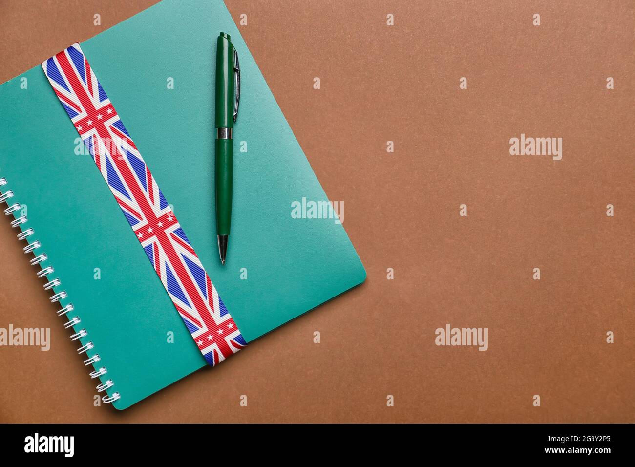 Notebook, pen and ribbon in colors of UK flag on color background ...