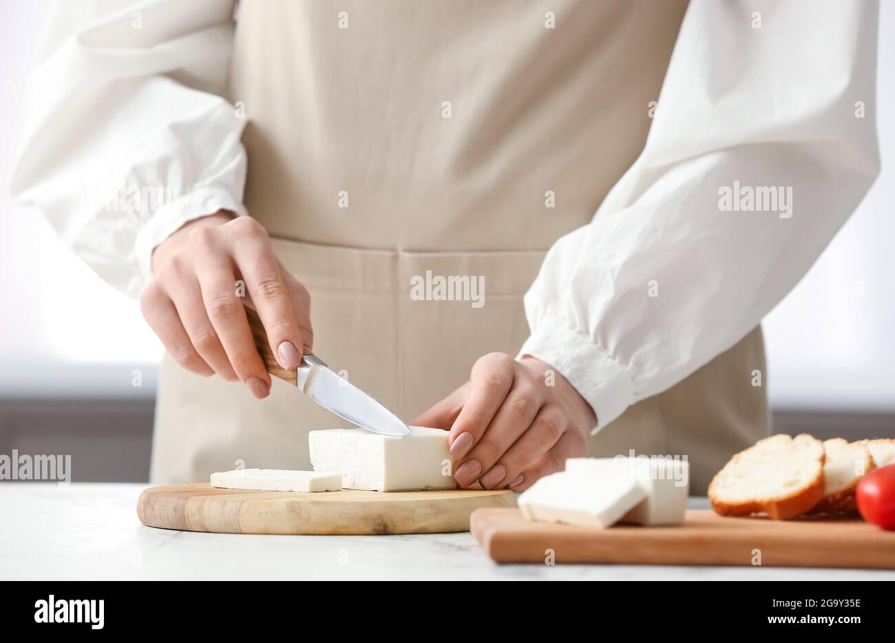 Woman cutting delicious feta cheese on table Stock Photo - Alamy