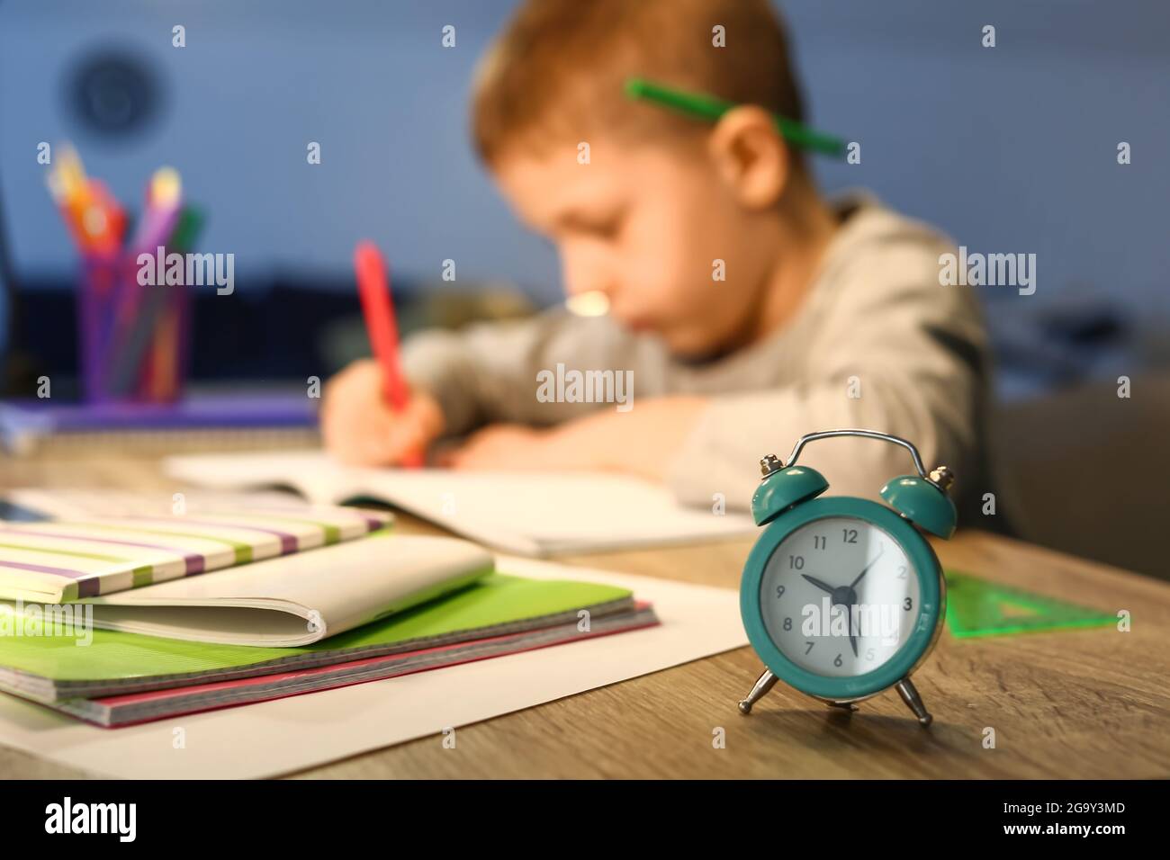 Alarm clock on table of little boy doing homework at home late in ...