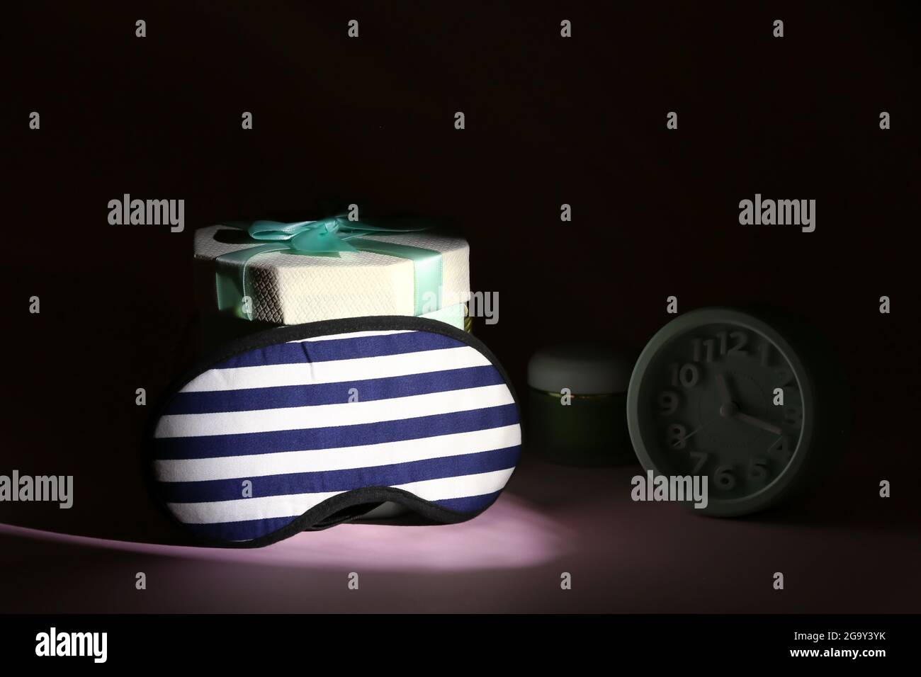 Stylish sleeping mask, clock and gift box on dark background Stock ...