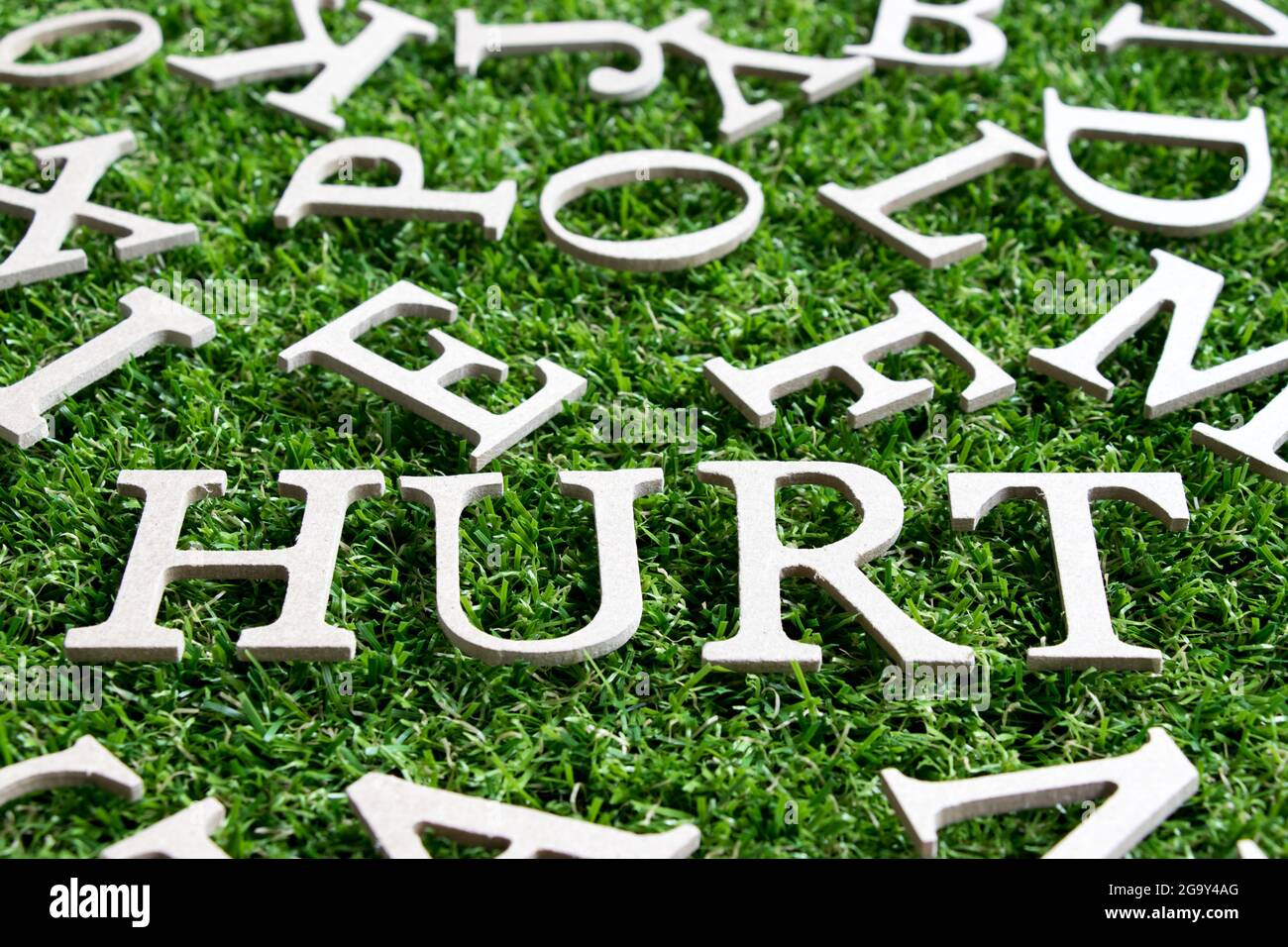 Wood alphabet in wording hurt on artificial green grass background ...