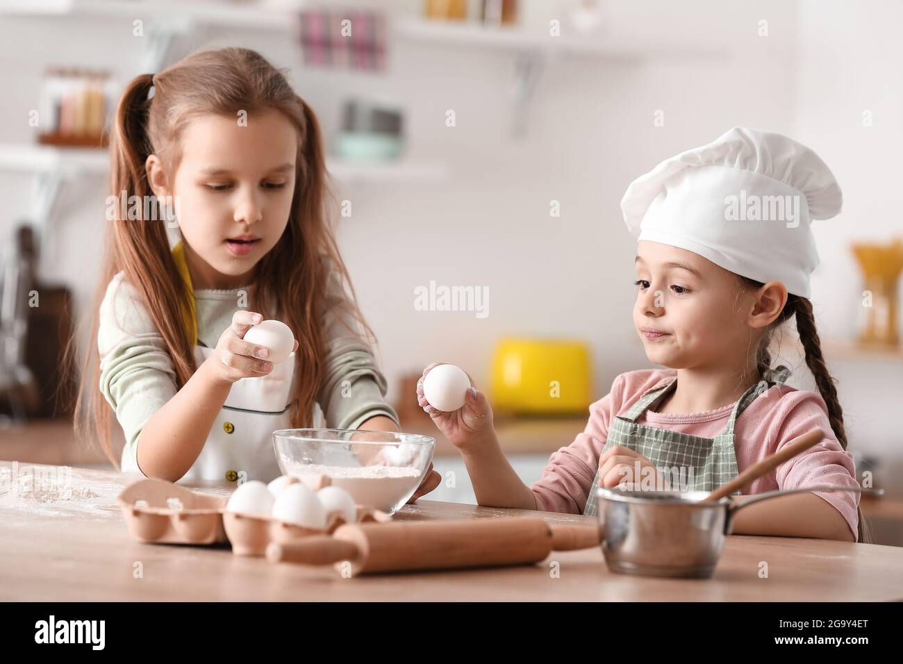 Cute little sisters cooking in kitchen Stock Photo - Alamy
