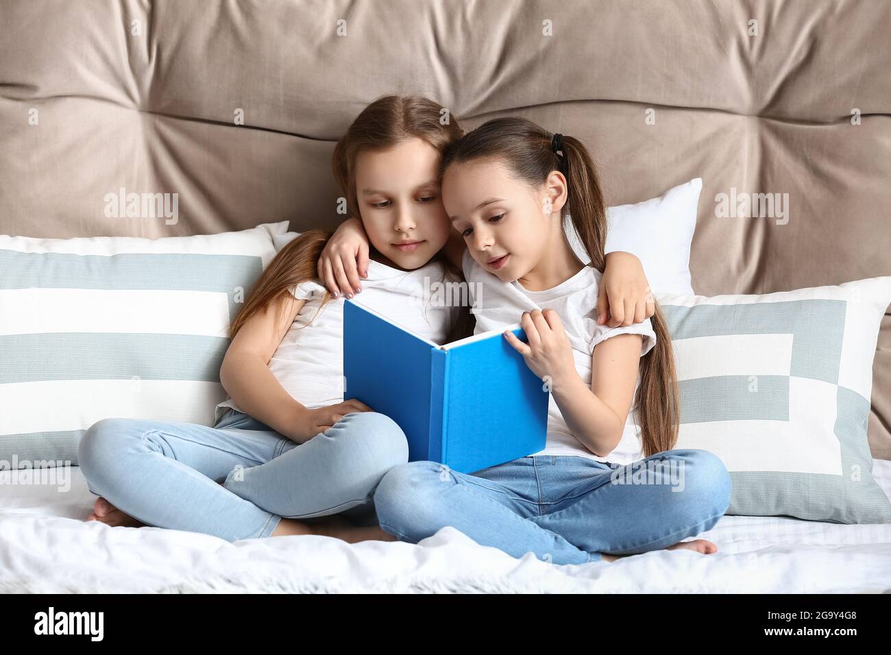 Cute little sisters reading book in bedroom Stock Photo - Alamy