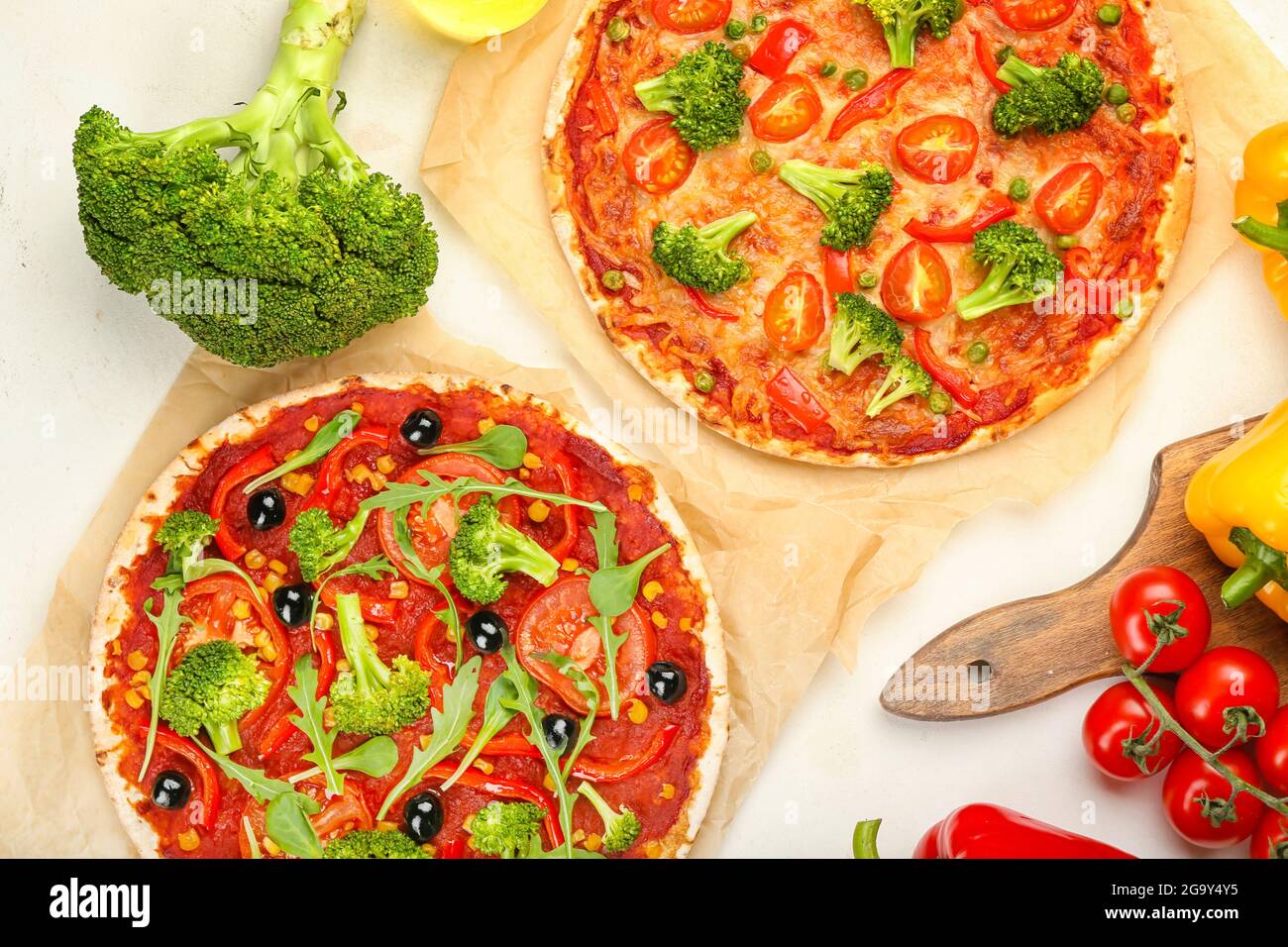 Parchment with tasty vegetarian pizzas on light background Stock Photo ...