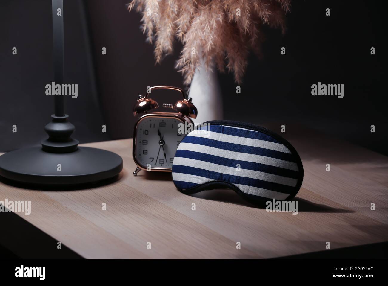 Sleeping mask with alarm clock on table in dark room Stock Photo - Alamy