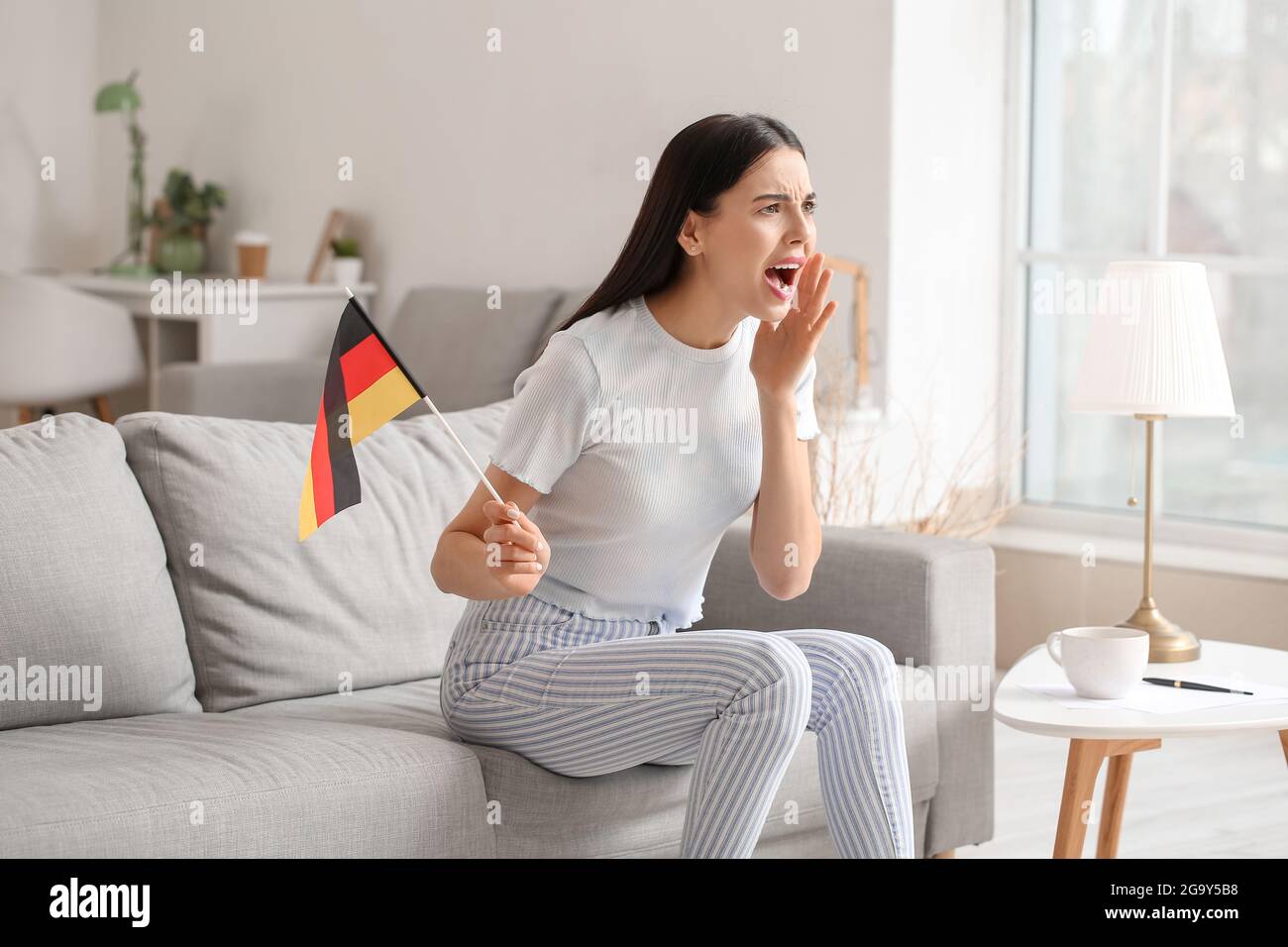 Screaming young woman with the flag of Germany at home Stock Photo - Alamy
