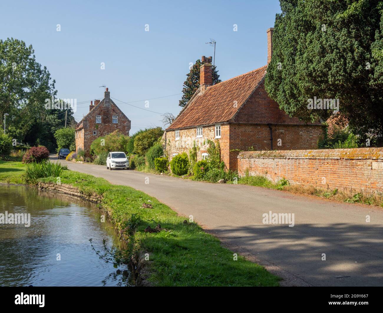 Idyllic English village scene in summer, view across a duck pond to an ...