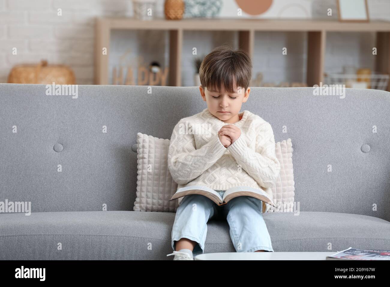 Little boy with Bible praying at home Stock Photo - Alamy
