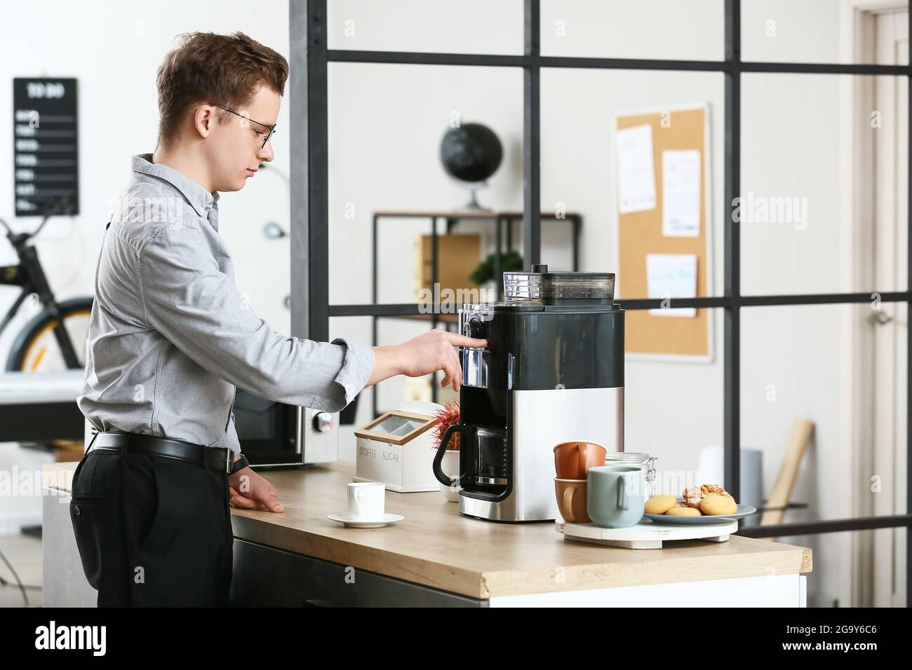 Young man making coffee in office Stock Photo - Alamy