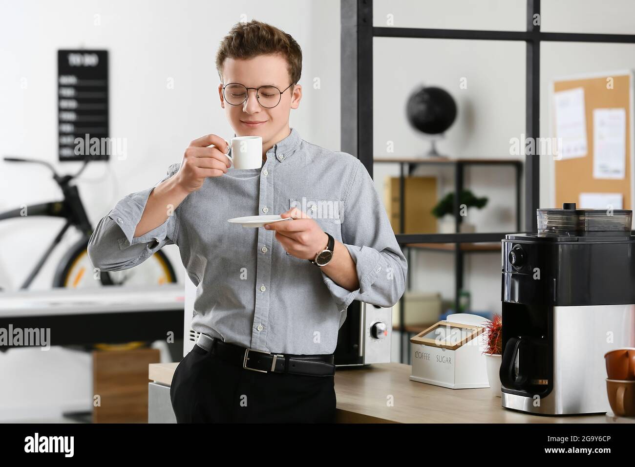 Young man drinking coffee in office Stock Photo - Alamy