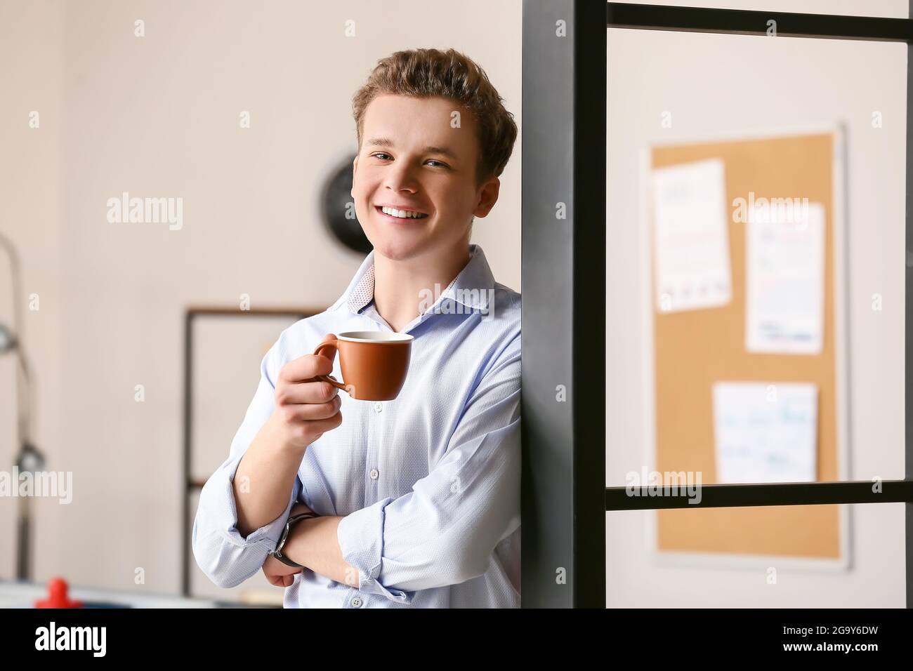 Young man drinking coffee in office Stock Photo - Alamy