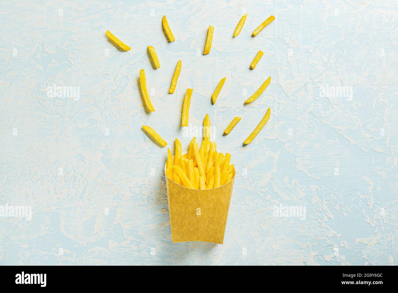 Paper bag with tasty french fries on color background Stock Photo - Alamy