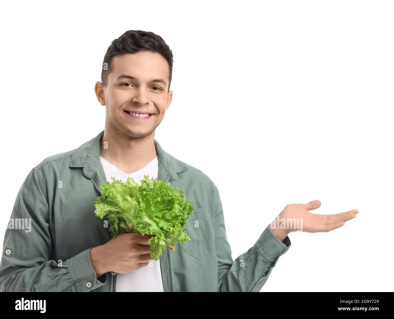 Young man with fresh lettuce showing something on white background ...
