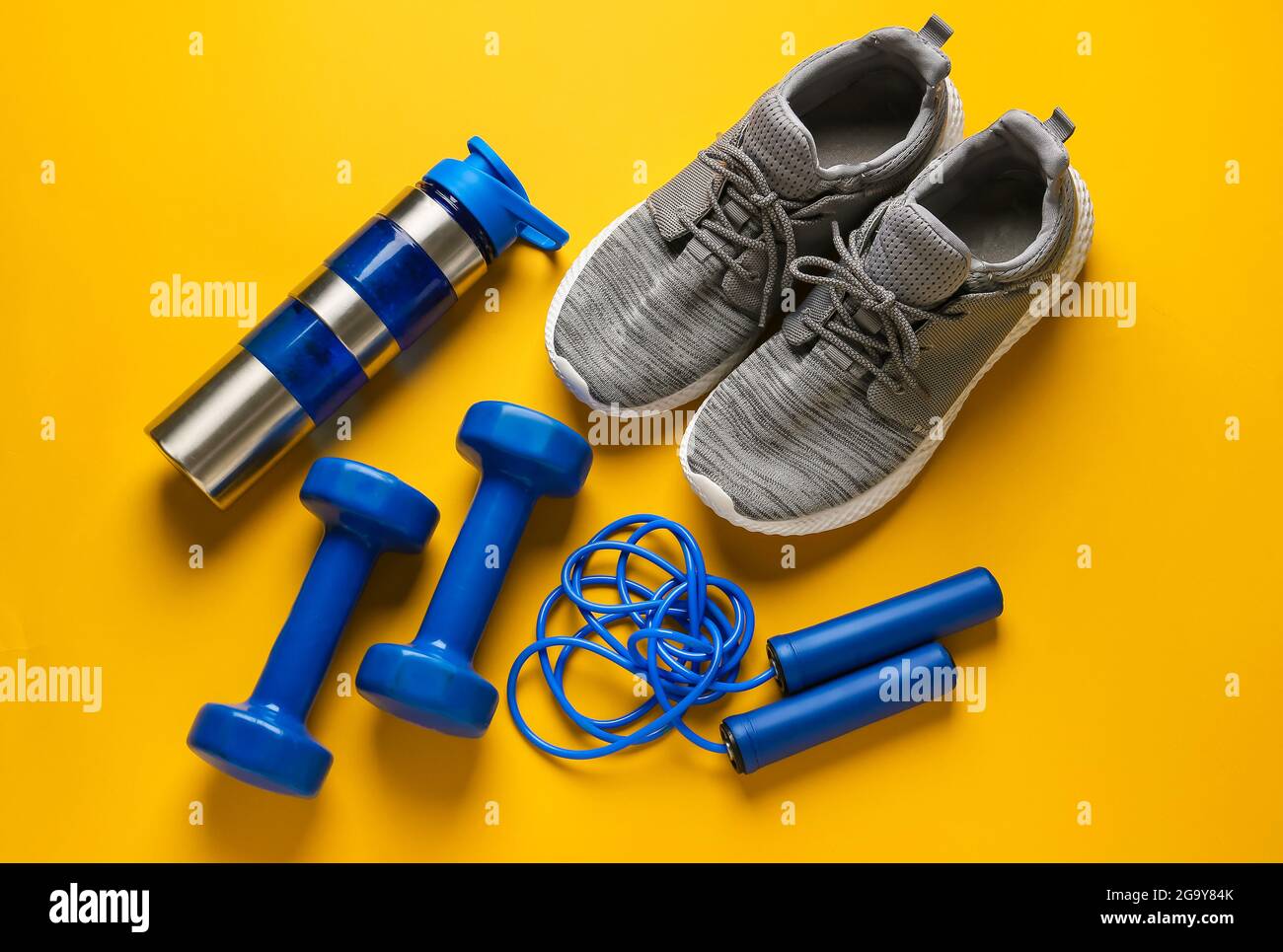 Sport shoes, bottle of water, skipping rope and dumbbells on color ...