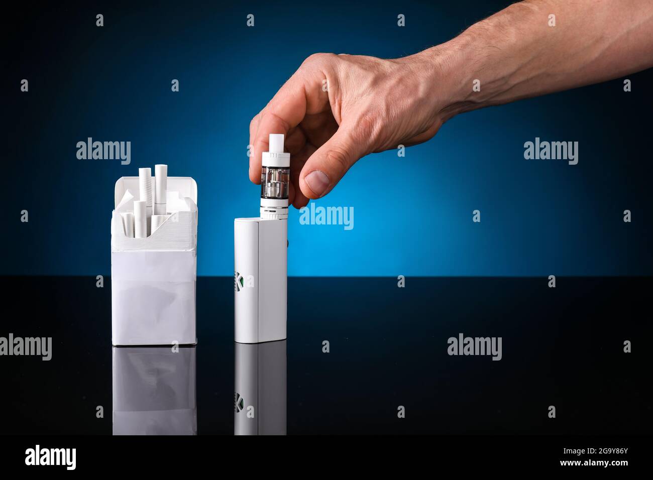 Male hand with vape mod and cigarettes in box on dark background Stock ...