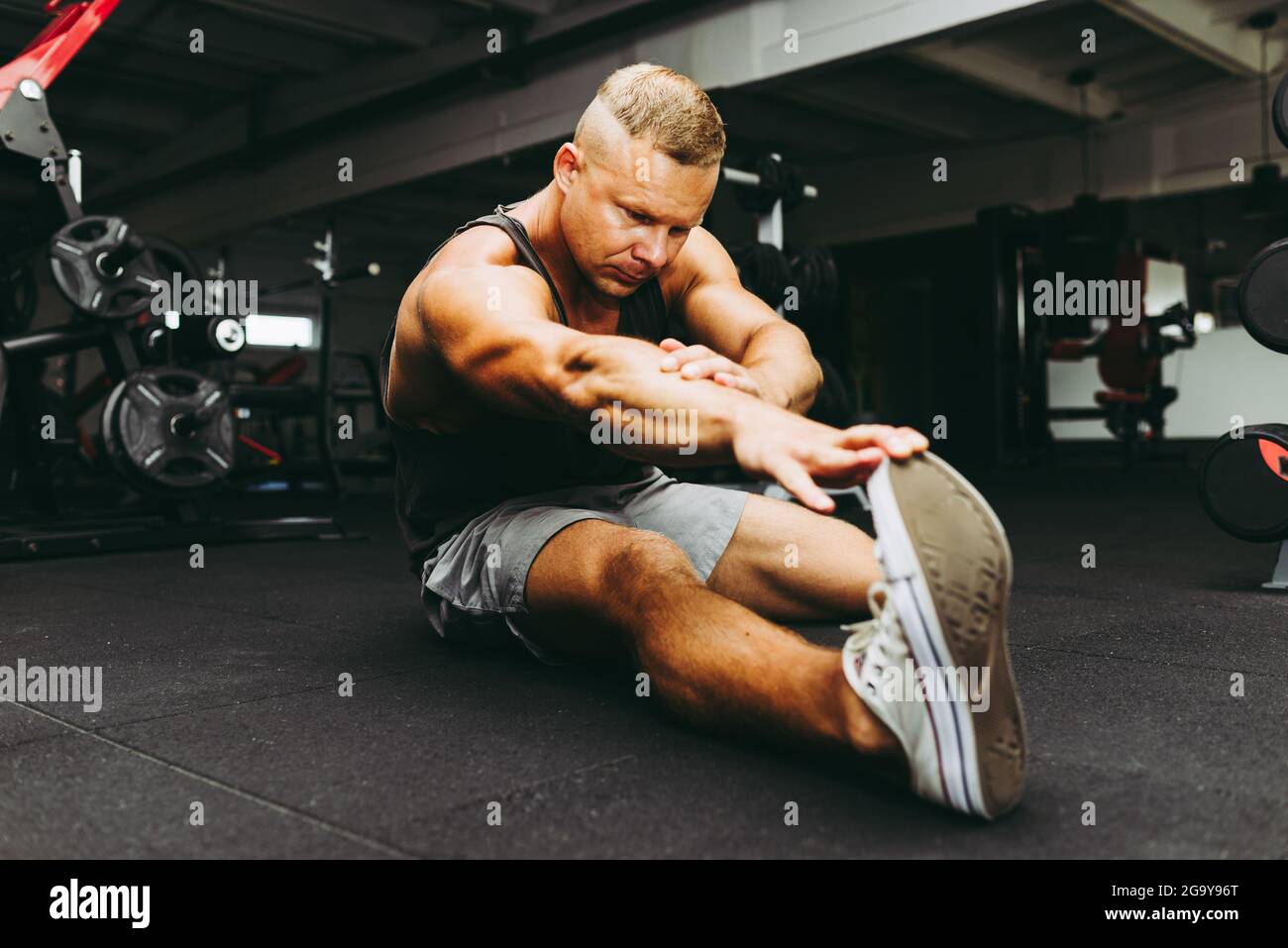 Man at the gym doing stretching exercises on the floor.Sports man at ...