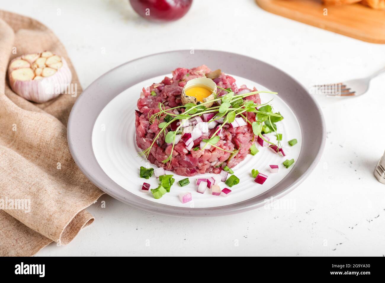 Plate with tasty beef tartare on light background Stock Photo - Alamy