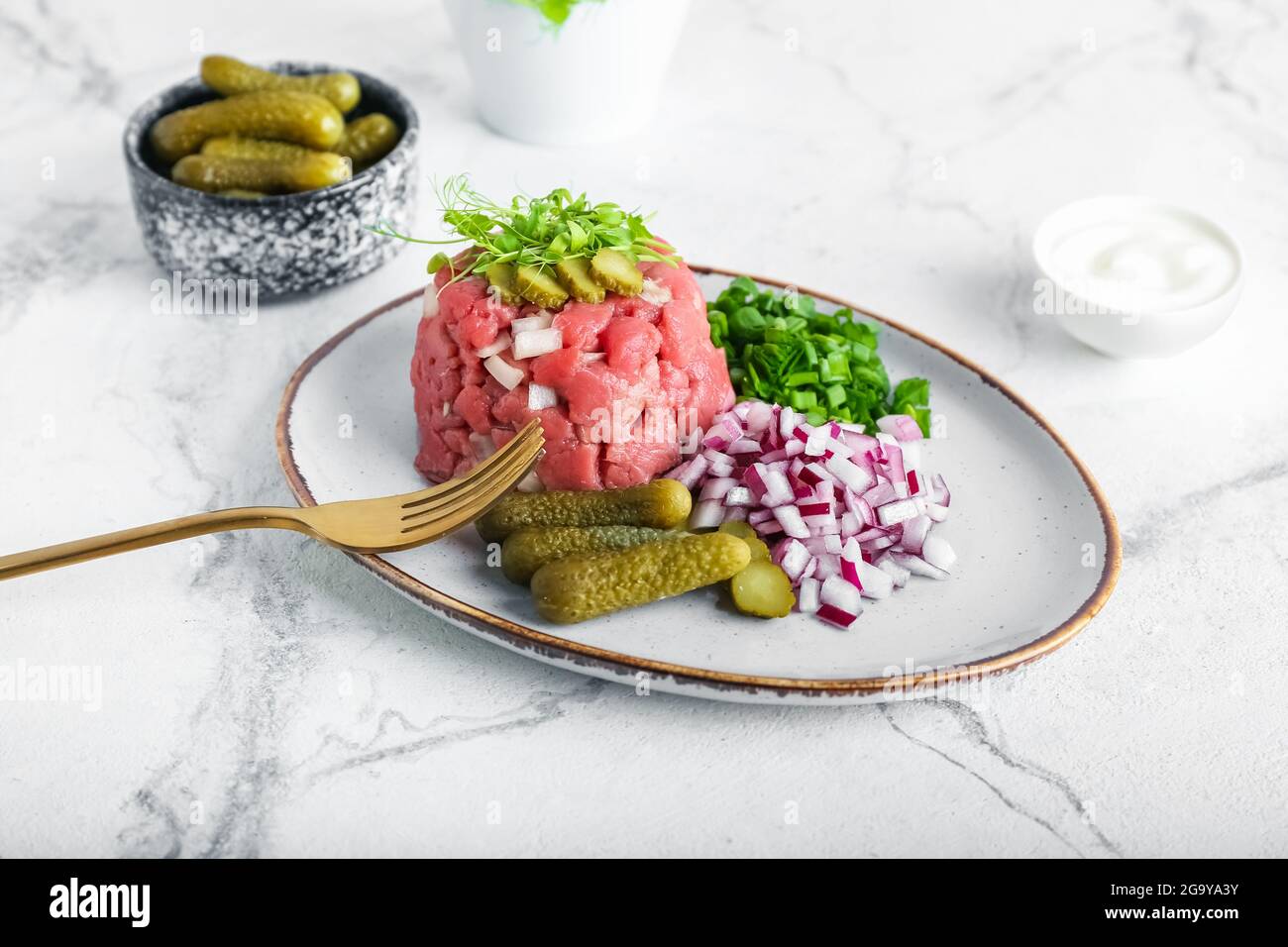 Plate with tasty beef tartare on light background Stock Photo - Alamy