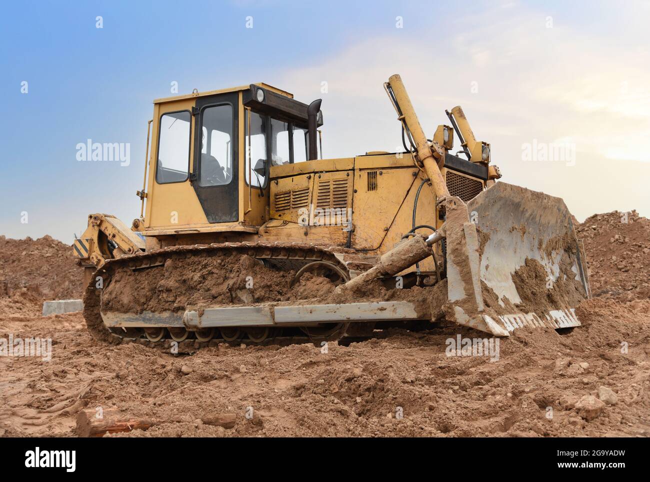 Dozer on earthmoving at construction site on sunset background ...