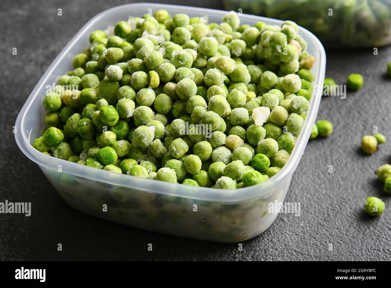 Container with frozen green peas on dark background Stock Photo - Alamy