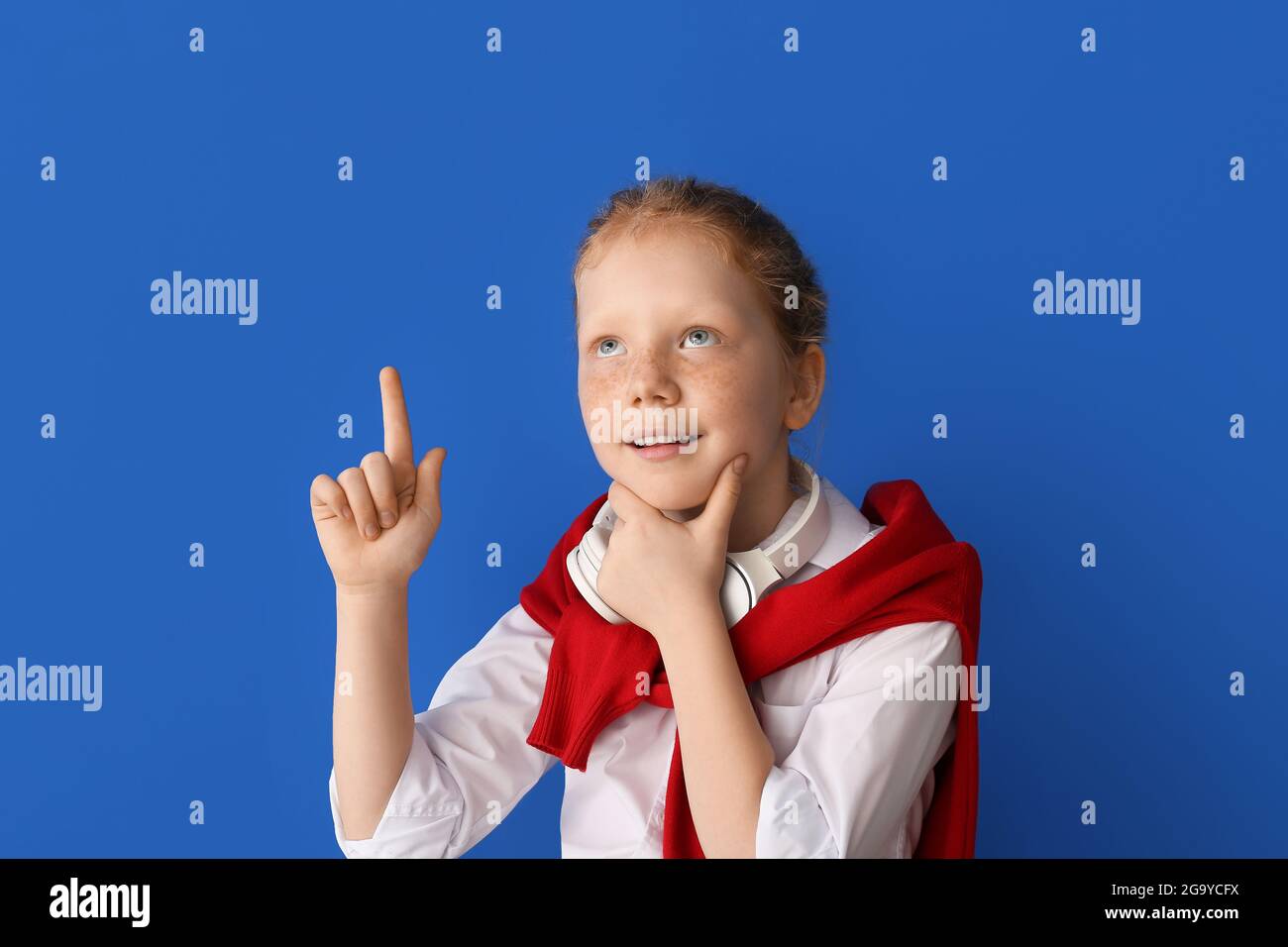 Cute little schoolgirl with raised index finger on color background ...