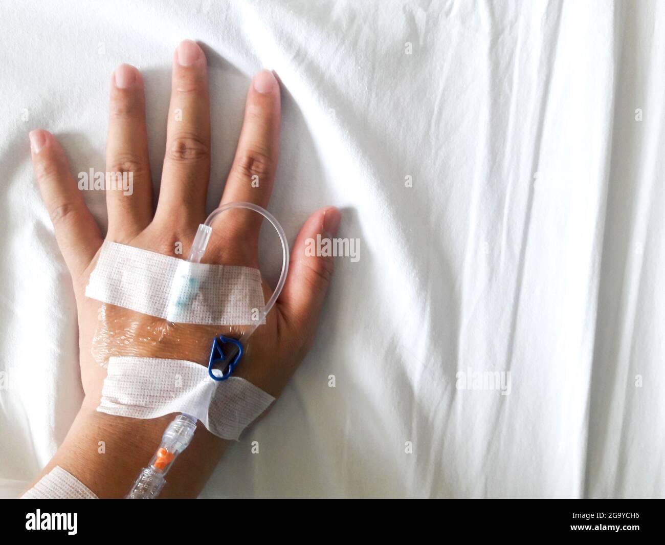 Patient hand with the tube of normal saline infusion on white cloth ...