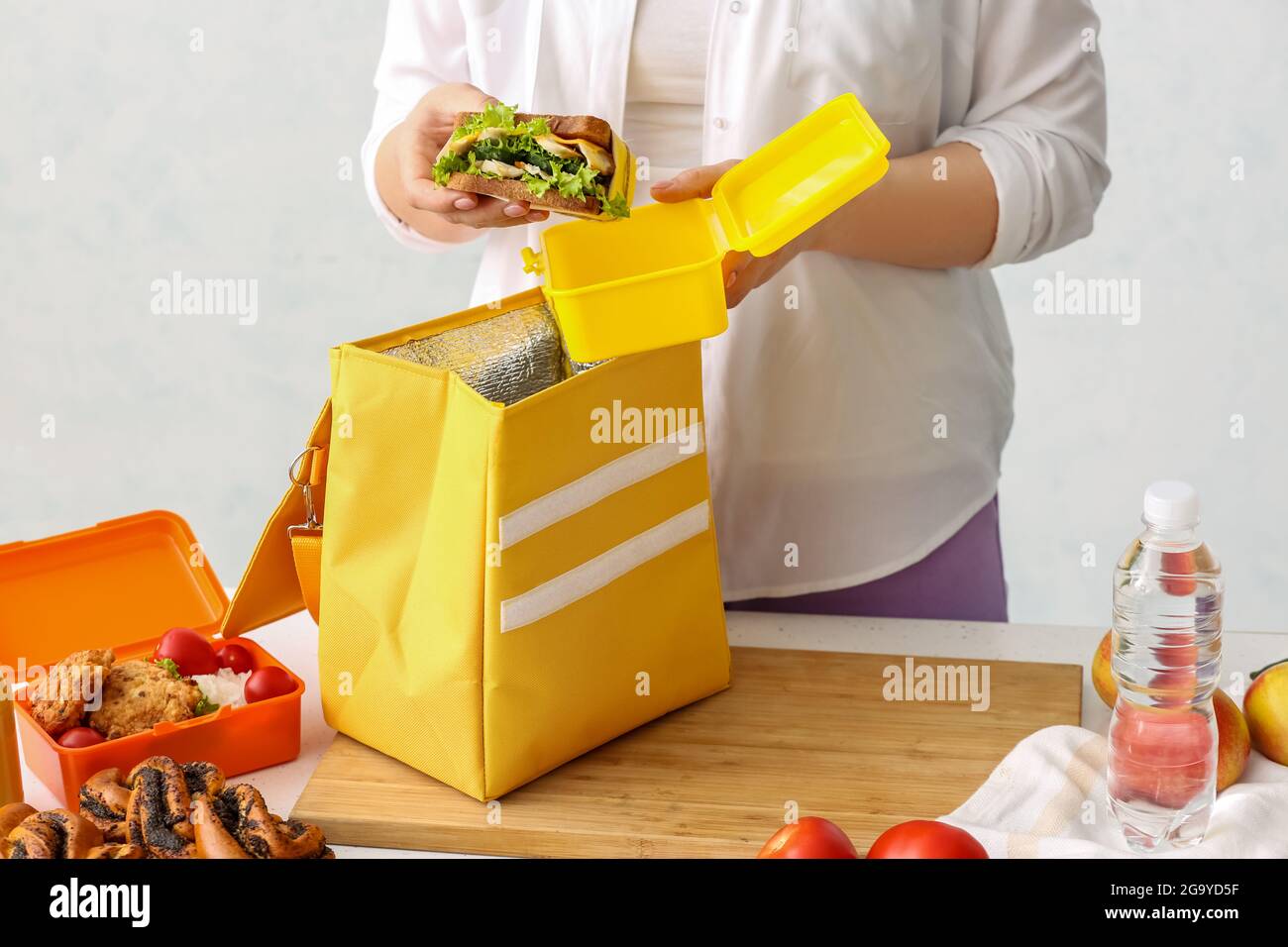 Woman packing meal into lunch box bag on light background Stock Photo ...