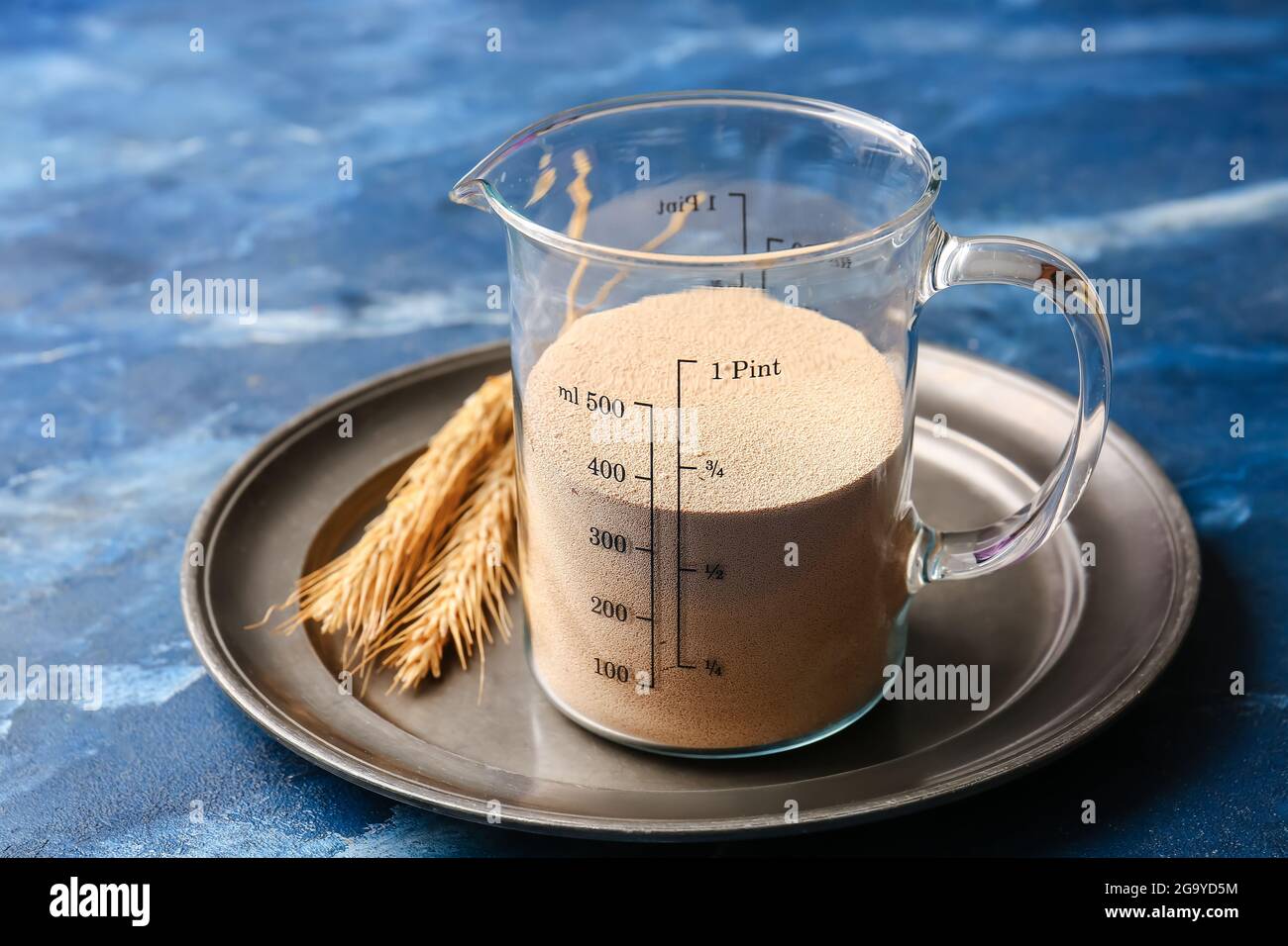 Measuring jug with active dry yeast on color background Stock Photo - Alamy