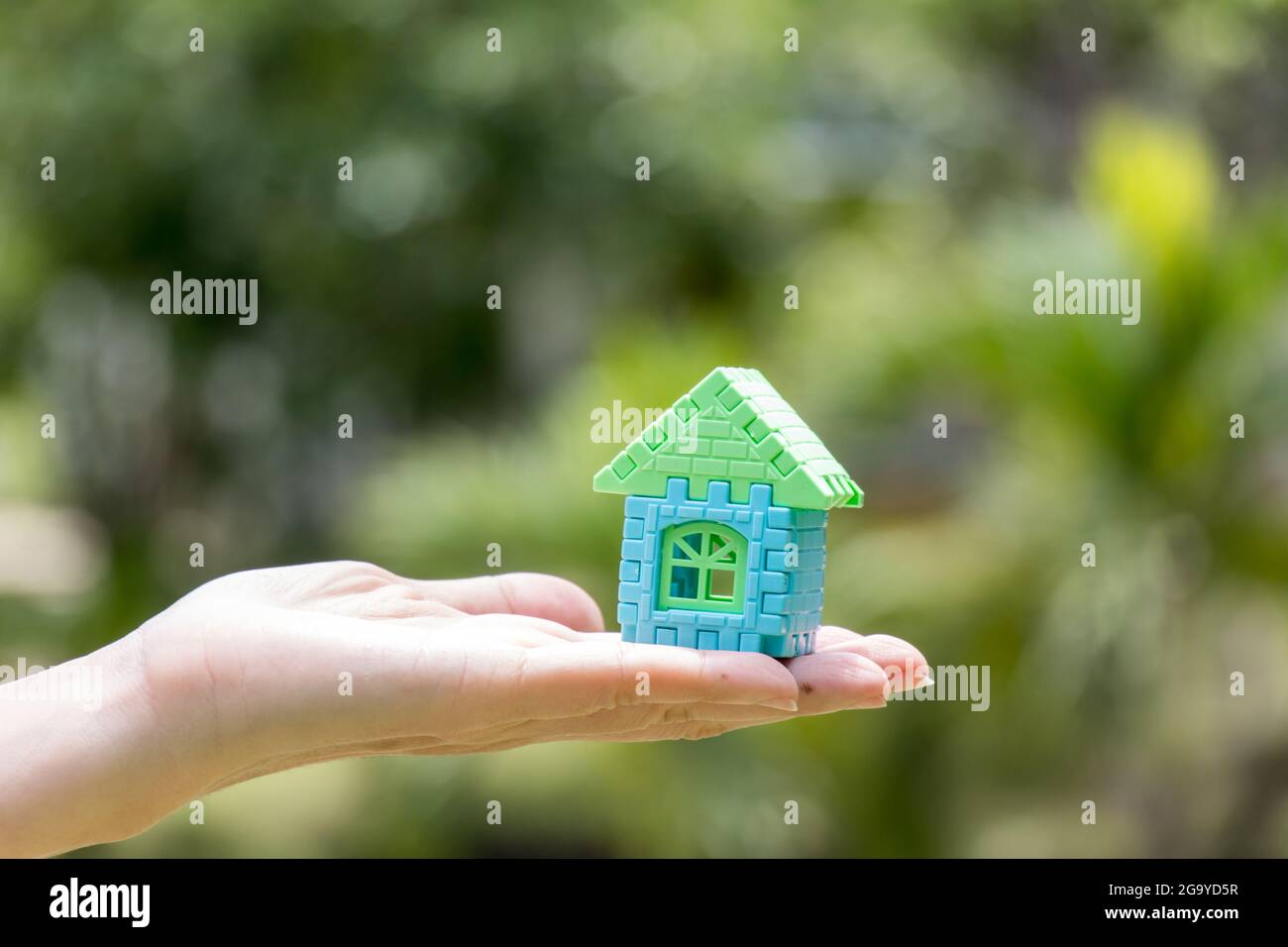 Woman hand hold home block model with blur green background (Concept ...