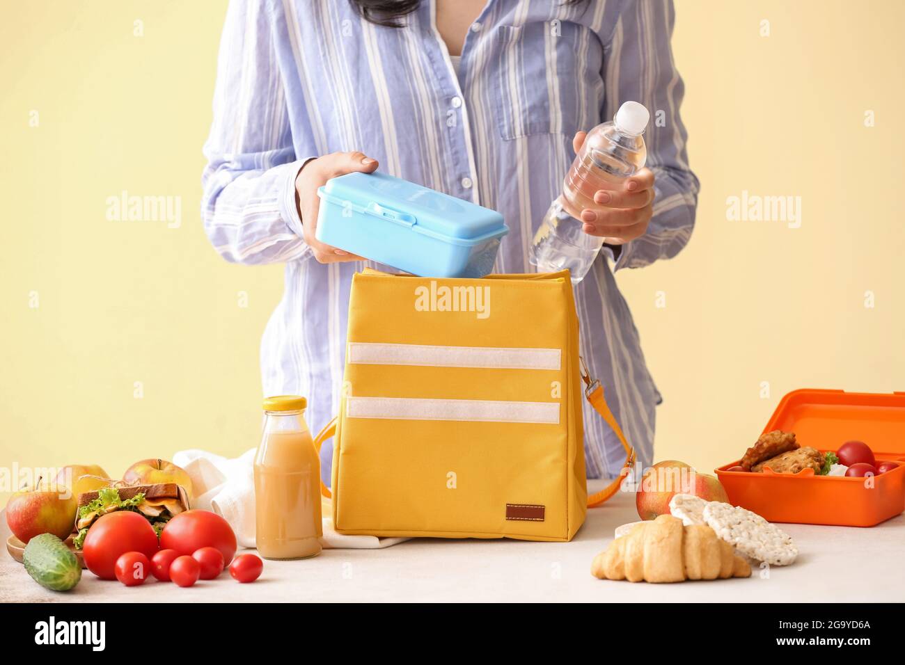 Woman packing meal into lunch box bag on color background Stock Photo ...