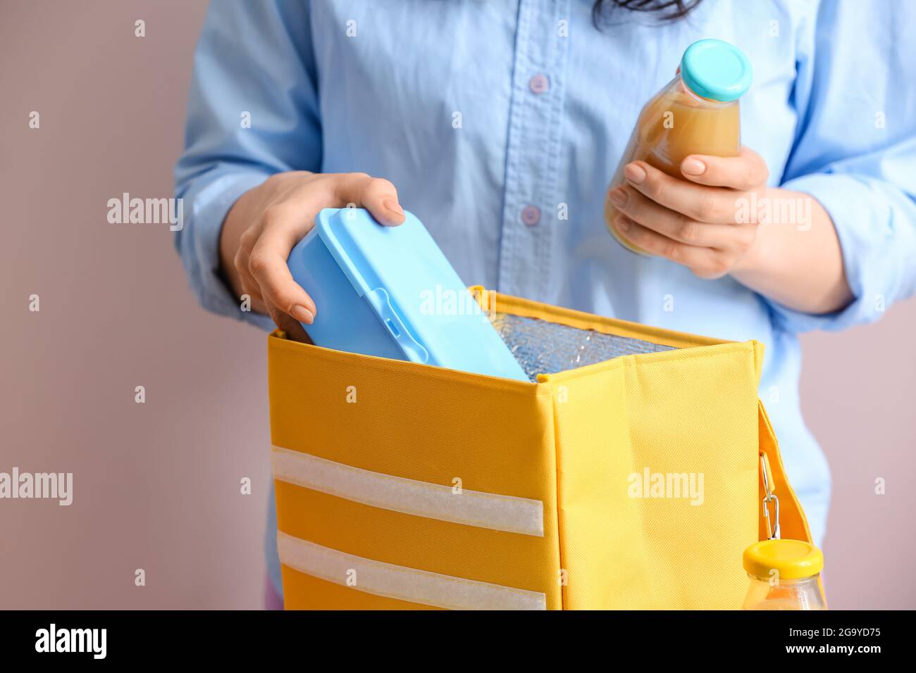 Woman packing meal into lunch box bag on color background Stock Photo ...