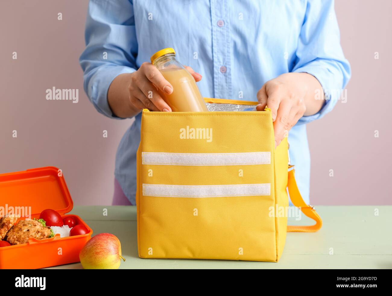 Woman packing meal into lunch box bag on color background Stock Photo ...