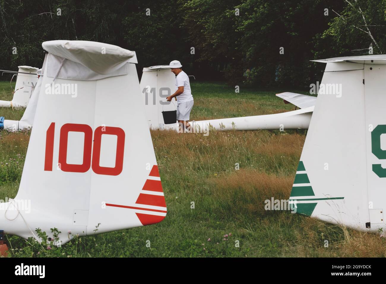Man prepares and checks gliders parked in the field,ready to fly. Small ...