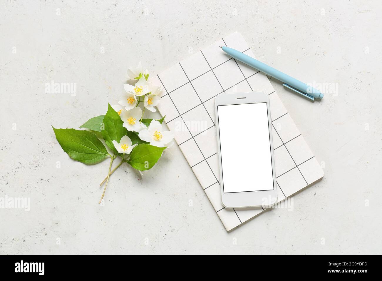 Mobile phone, notebook, pen and jasmine flowers on light background ...