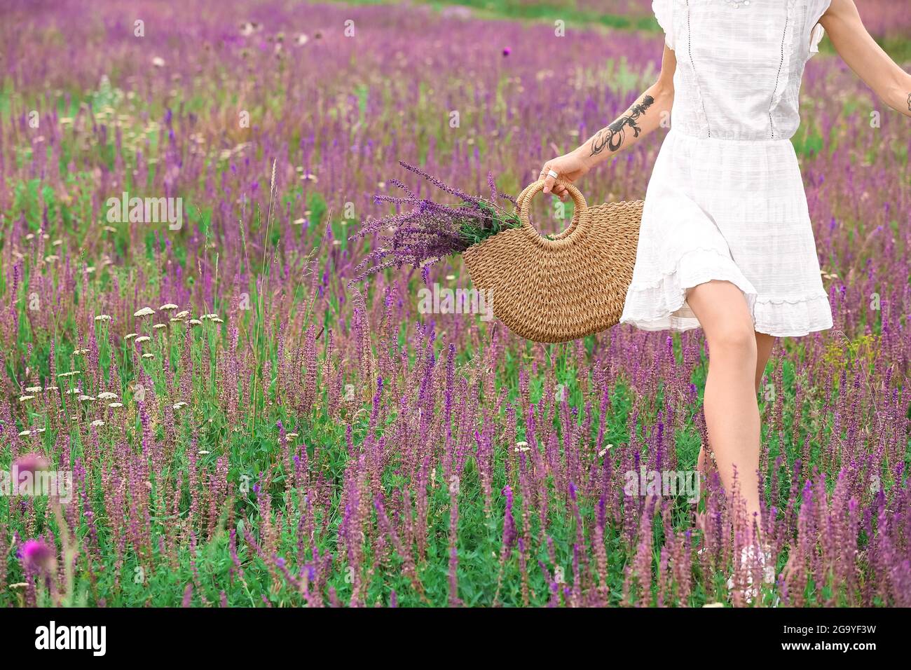Beautiful young woman with flowers in bag on summer day Stock Photo - Alamy