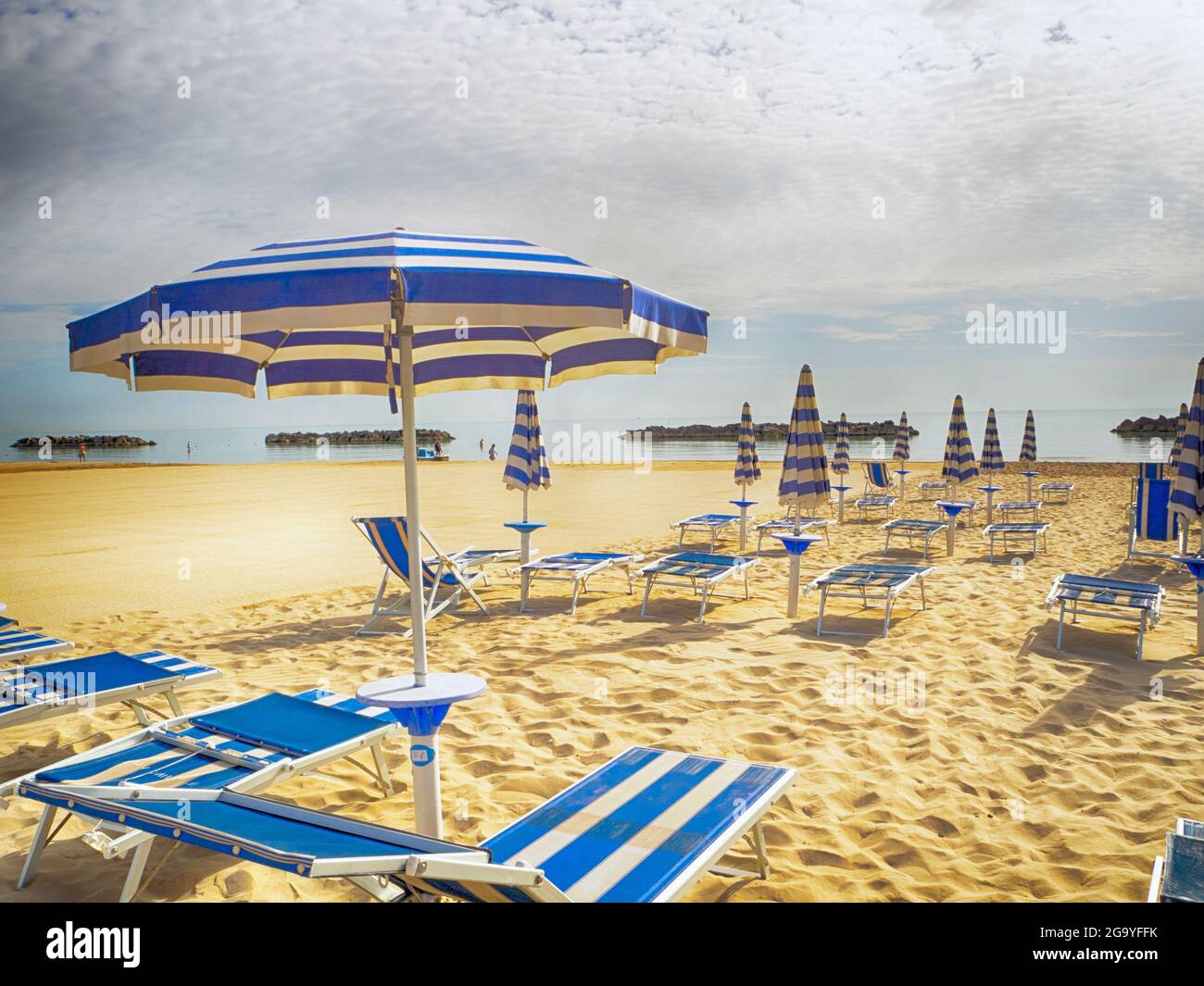 Striped sun loungers and parasols on beach, Italy Stock Photo - Alamy