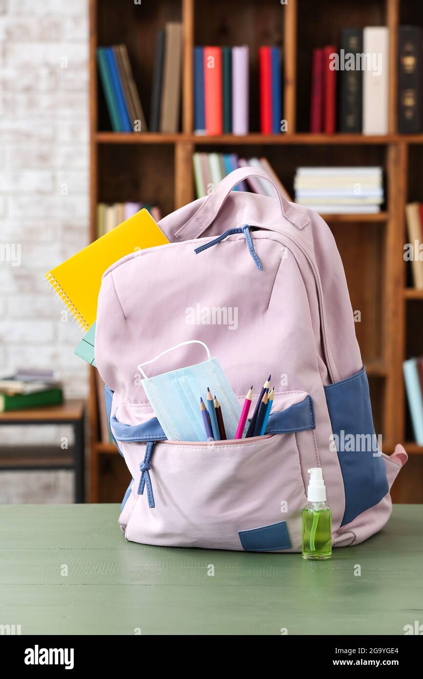 School backpack with stationery on table in classroom Stock Photo - Alamy